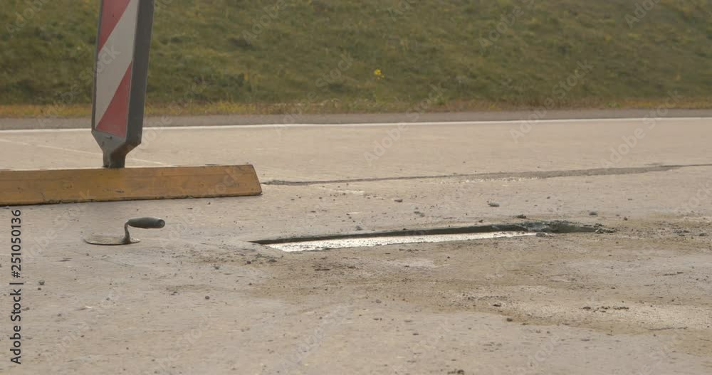 Close up of pit in asphalt road repaired with concrete patch at road ...