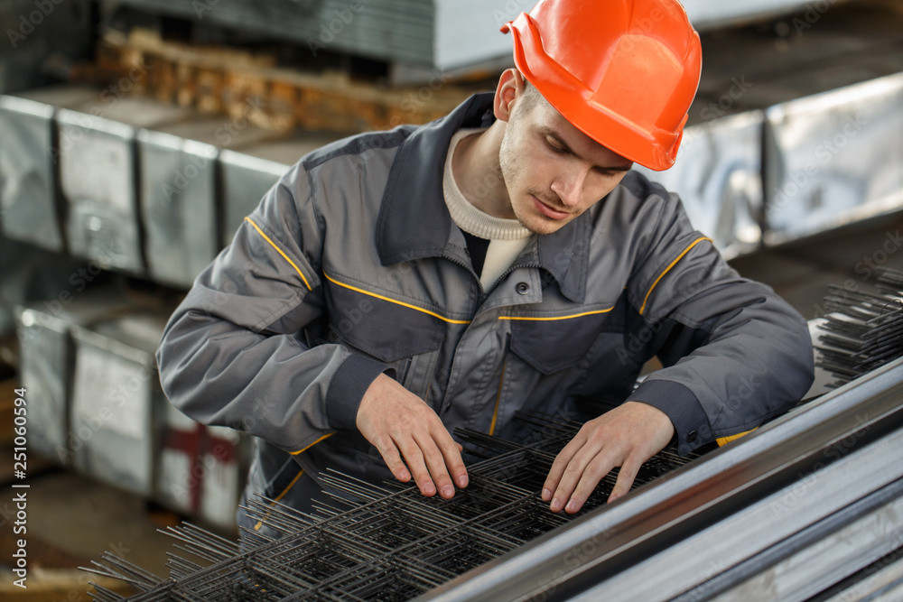 Young male worker wearing orange hardhat and gray protective suit ...