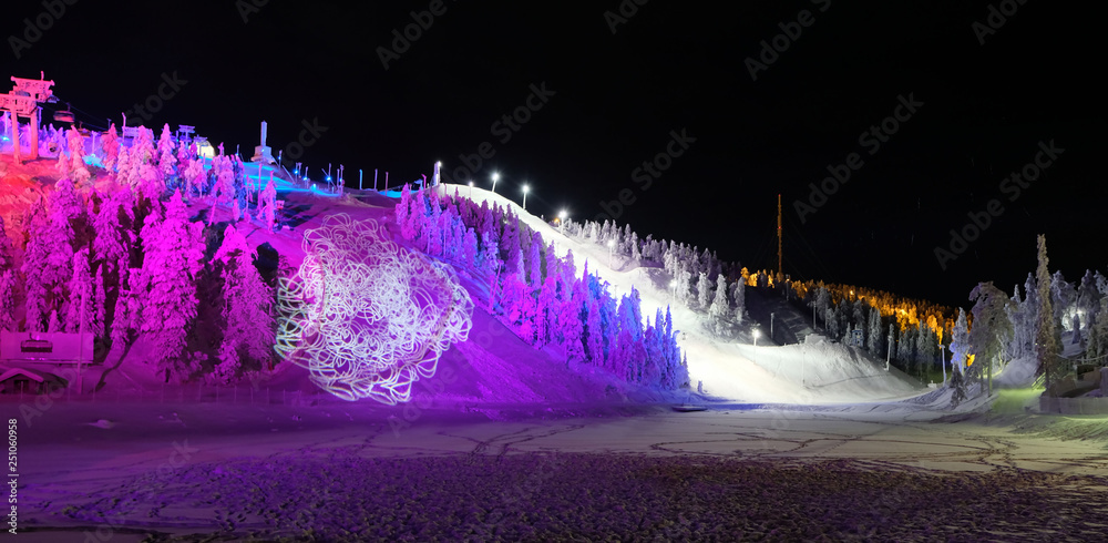 Ruka mountain in the evening lit up with colorful spotlights. Winter ...
