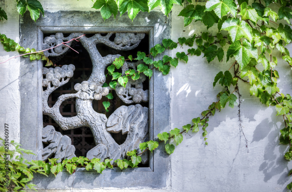 Stone carving of a tree as decoration for a window in a wall in China ...