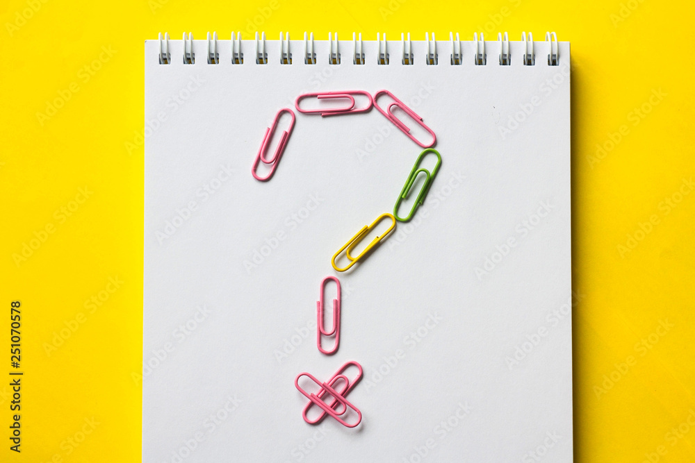 Notepad on yellow background with paper clips and question mark Stock ...