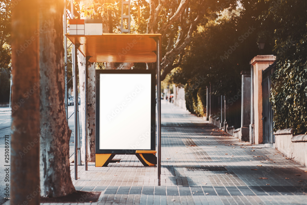Urban bus stop near the road with poster placeholder inside; vertical ...