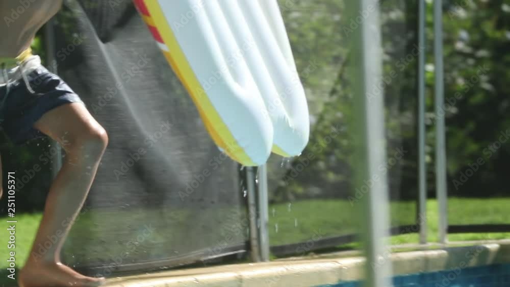 Boy jumping on top of inflatable mattress at the swimming pool ...