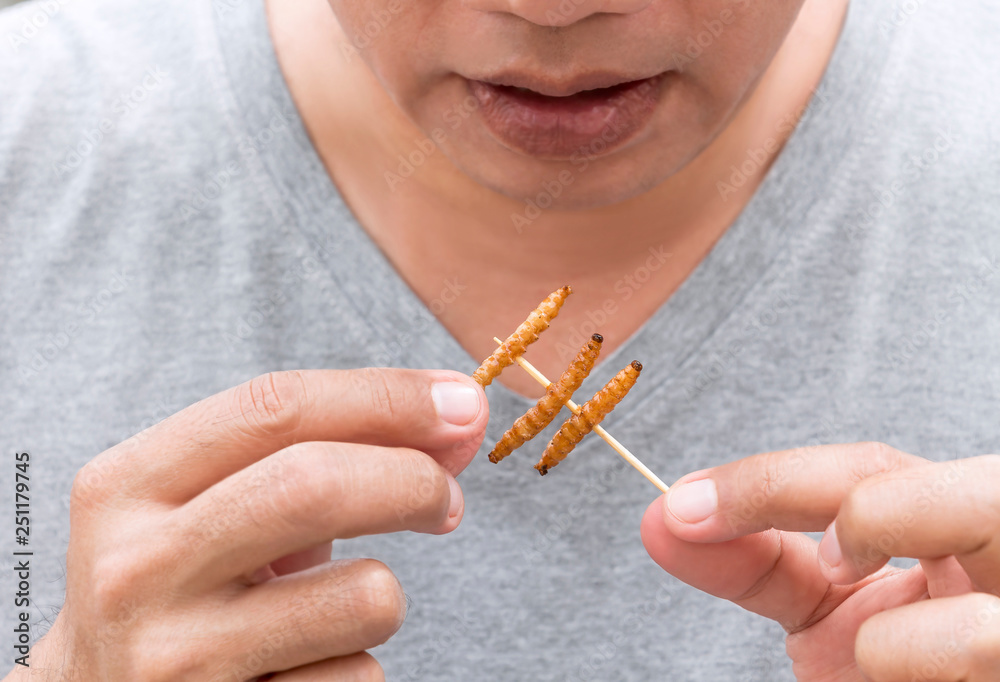 Food Insects: Man eating Bamboo Worm on wooden skewer. Bamboo ...