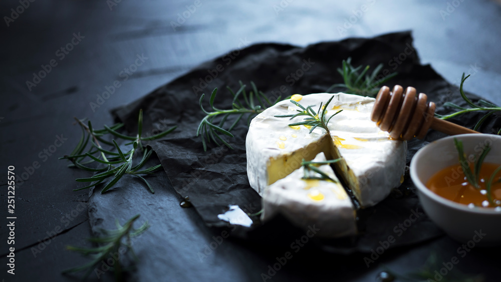 Сamembert cheese with rosemary and honey on black slate background ...