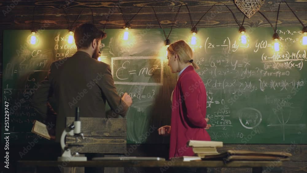 Bearded professor and girl student decide formulas that are written on ...