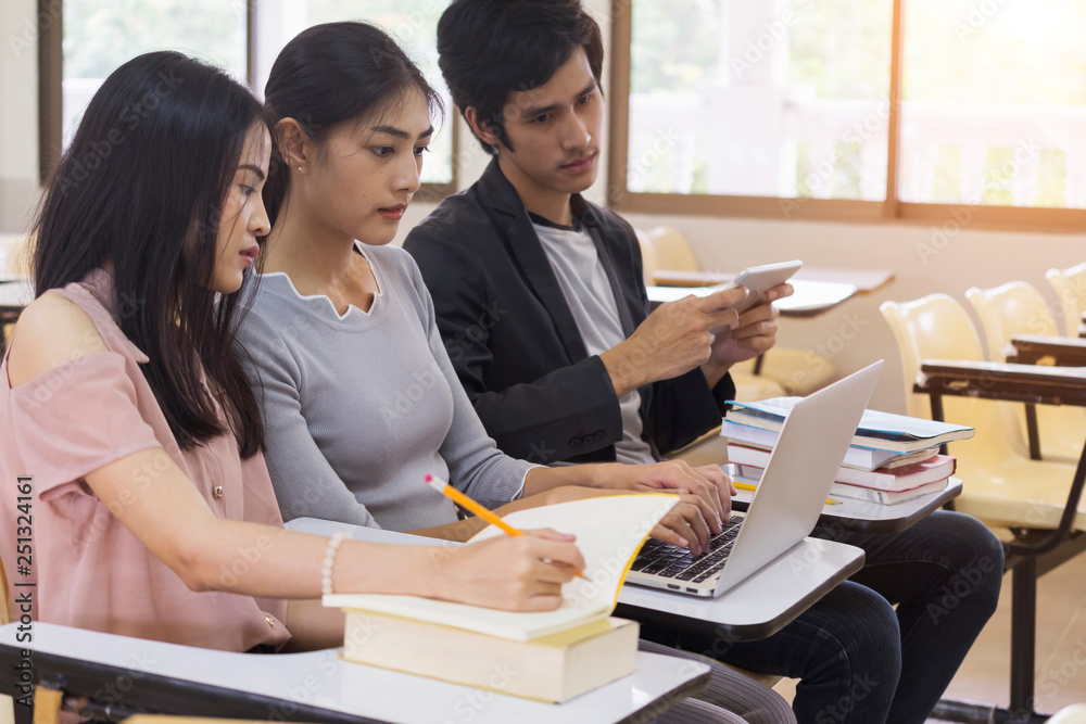 Young college students studying for a test together, using computer ...