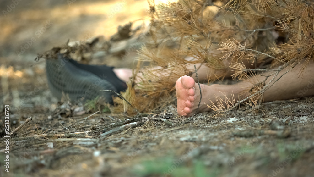 Corpse in one shoe covered with tree branch lying on ground, murder in ...