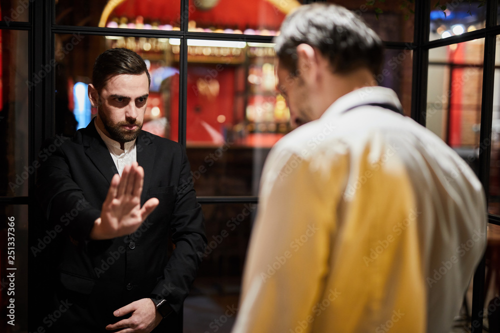 Portrait of restaurant security guard stopping drunk man from entering ...