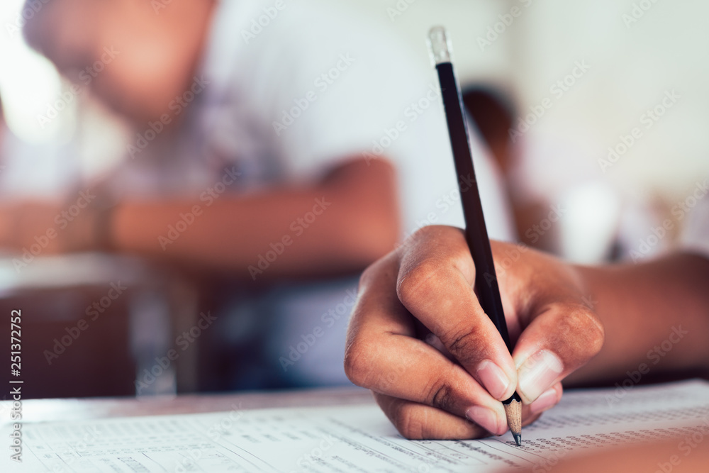 School student is taking exam and writing answer in classroom for ...