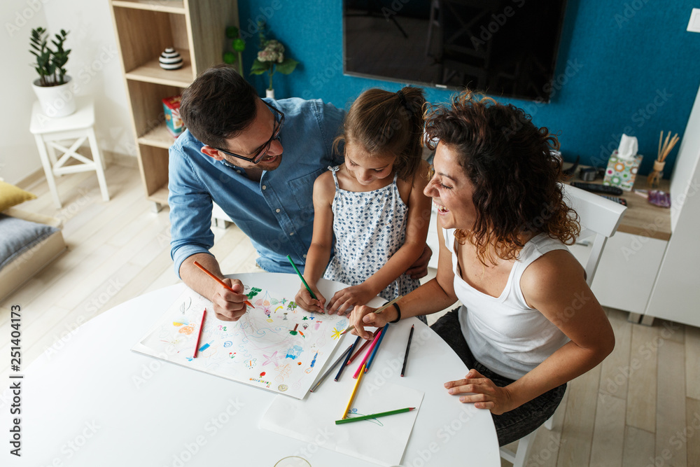 Parents teach they young daughter to draw.They sitting in living room ...