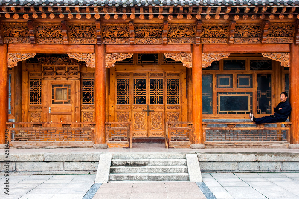 Traditional Wooden Chinese Architecture Of The House And A Sitting Man ...