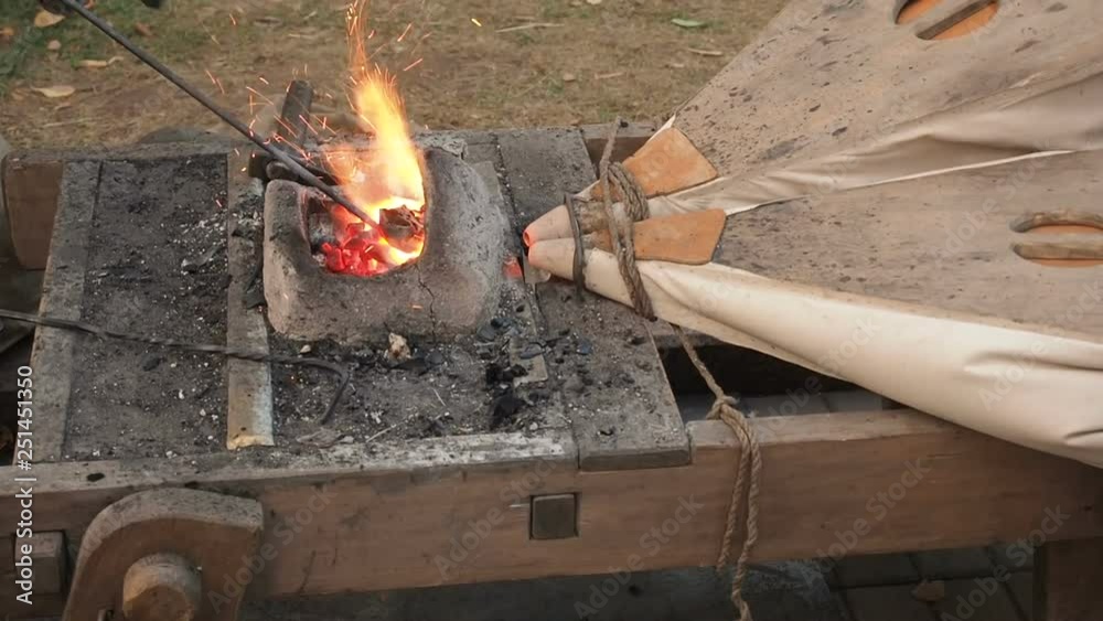 Blacksmiths working old fashioned bellows at the forge. The blacksmith ...