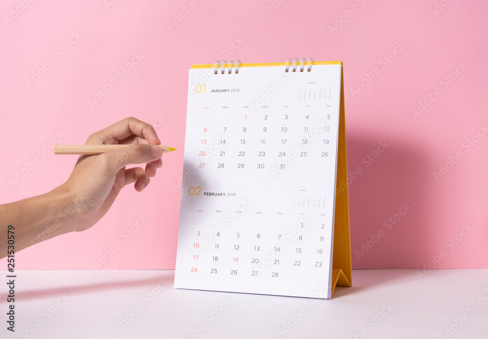 Hand holding pencil for writing marking on paper spiral calendar year ...