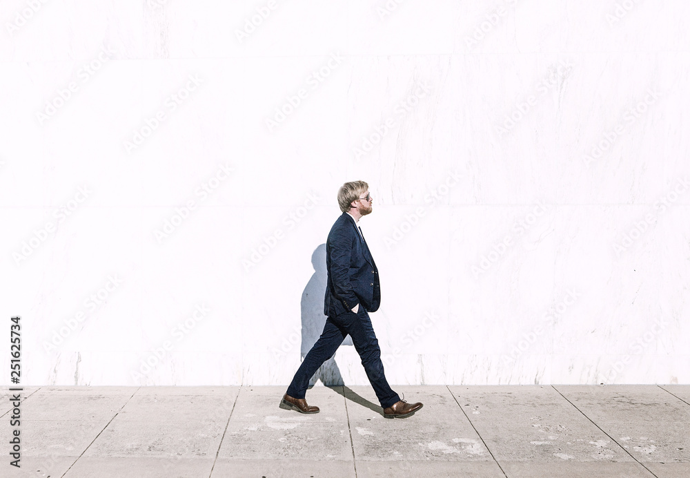 Side view of man walking on sidewalk Stock Photo | Adobe Stock