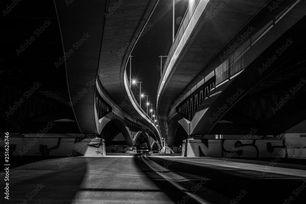 Under a large bridge at night, a massive bridge construction at night ...