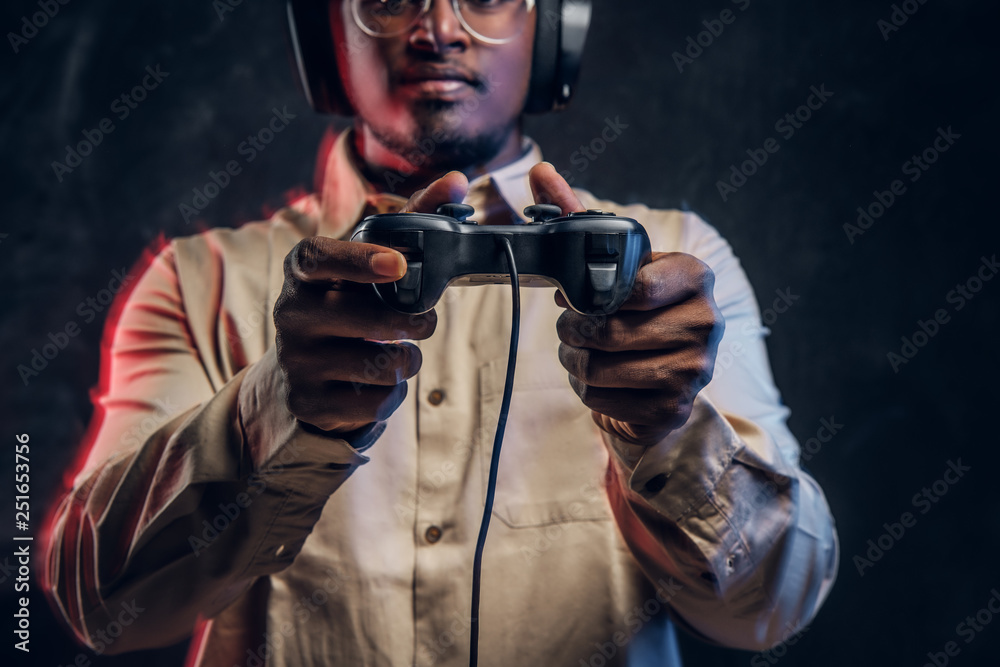 Cropped photo of a dark-skinned player with headphones and a game ...