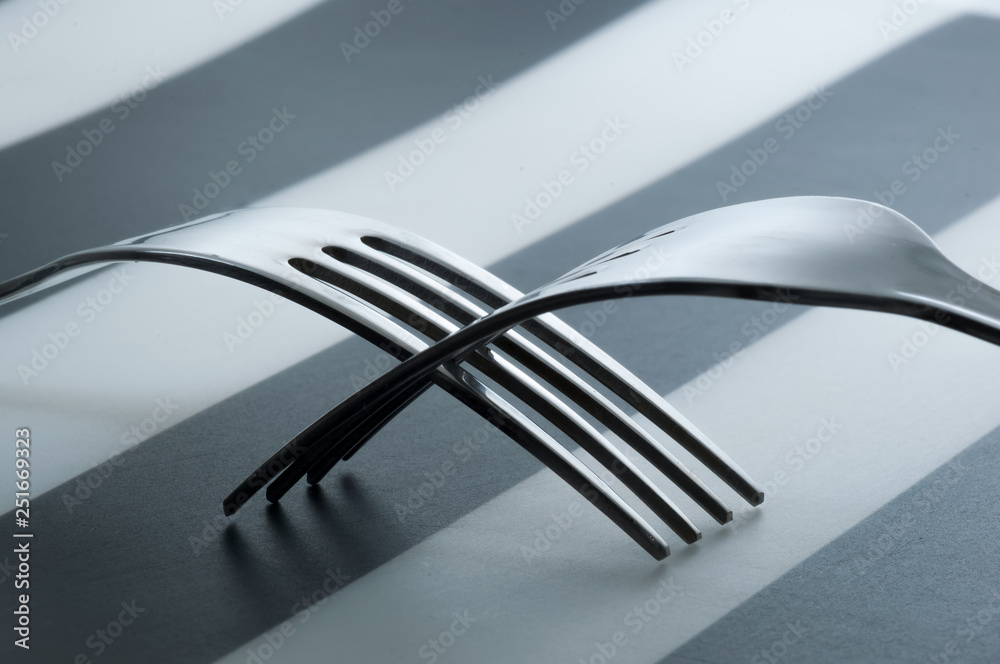 Two forks cross on striped background. 2 forks laying next to each ...