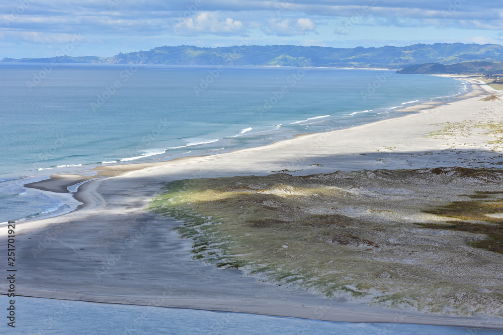 Flat tidal sandy coastal area partially shaded by clouds followed by ...