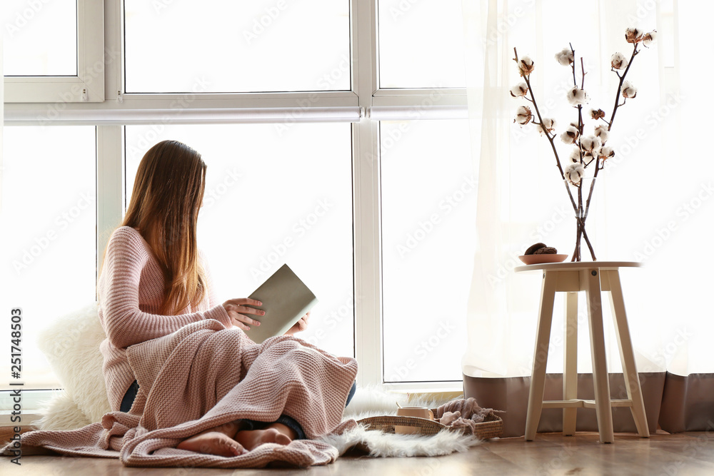 Young woman reading book near window Stock Photo | Adobe Stock