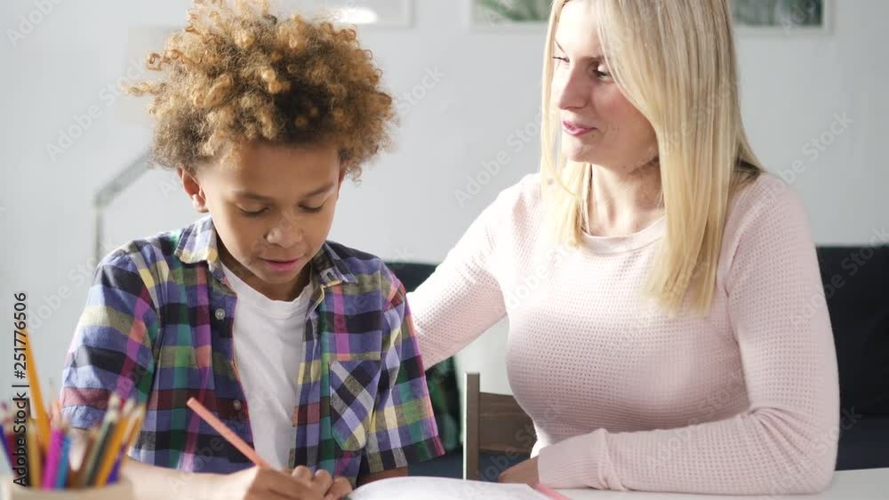 American adult woman is teaching and helping preteen hispanic boy with ...