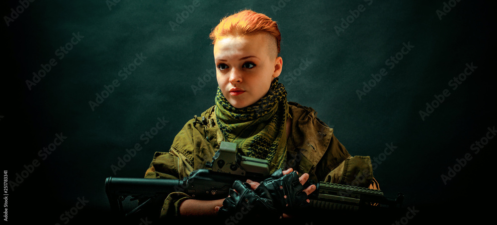 Woman with red hair in military uniform hold machine gun in darck room ...