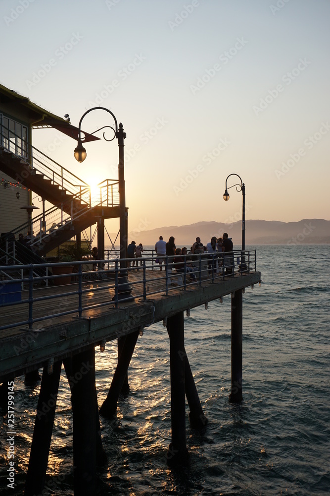 Muelle y playa en atardecer con colores cálidos y gente Stock Photo ...