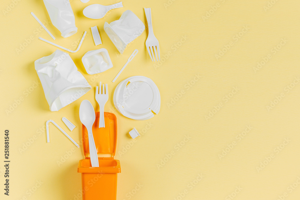White single use plastic in garbage bin on yellow background..Concept ...