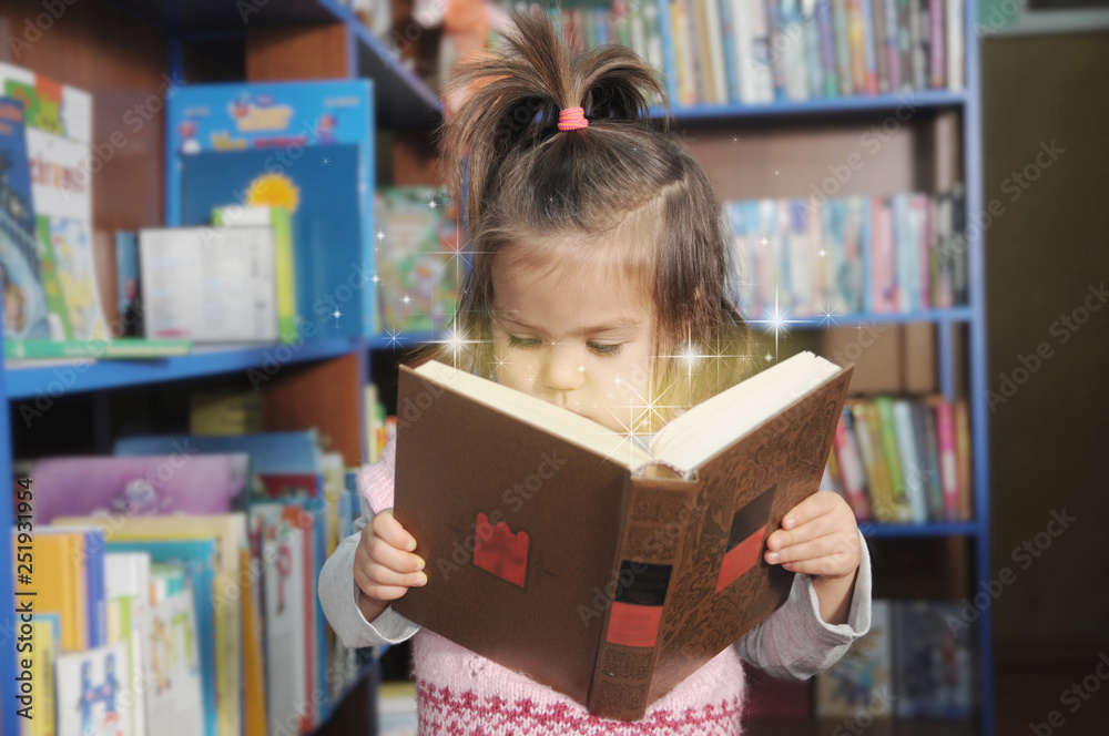 Child reading magic book. little girl in laibrary looking into fairy ...