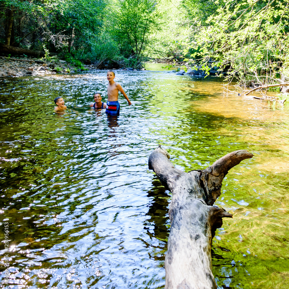 Mother with two children taking a bath in a small river in the forest ...