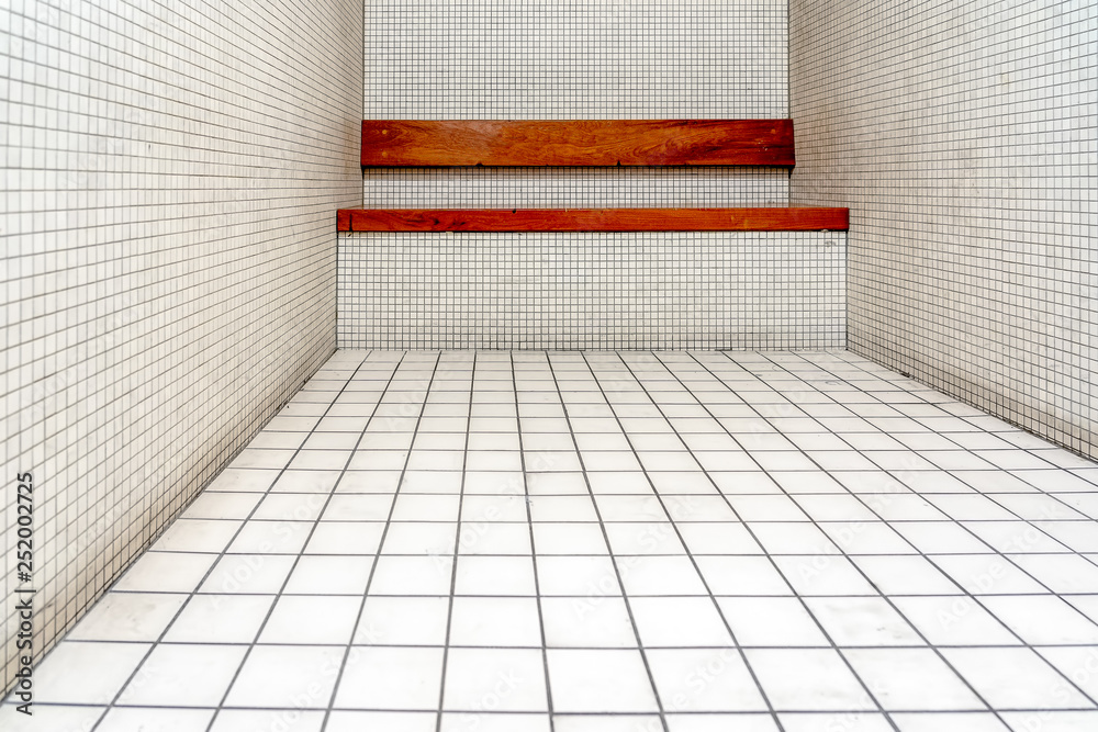 The very sober interior of a prison cell: bare tiled walls and a wooden ...