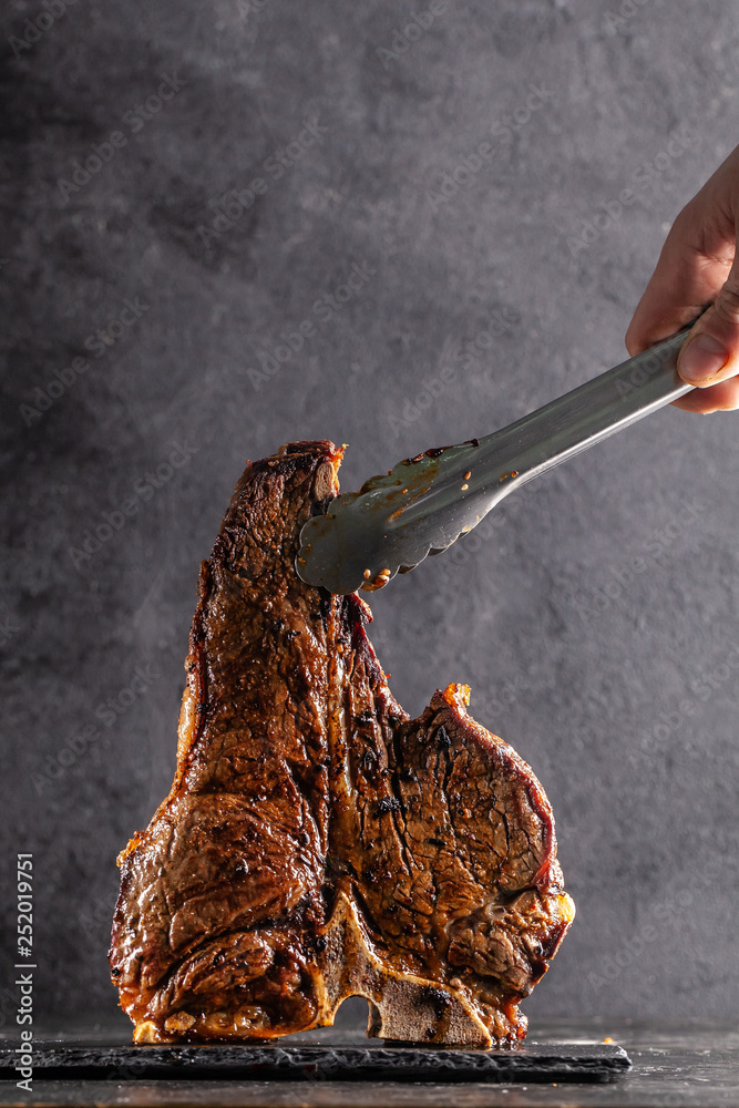 Large beef roast T-bone steak with smoke. Head chef holding steak meat ...