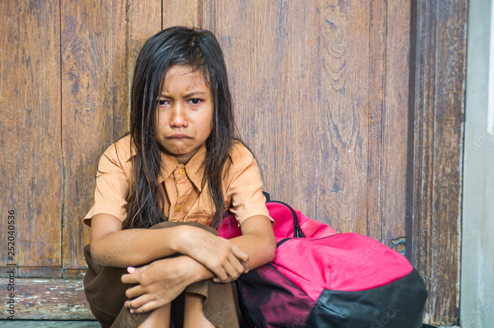 7 or 8 years child in school uniform sitting outdoors on the floor ...