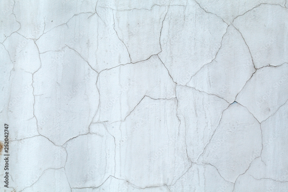 Gray concrete wall covered cracked plaster. Cracks on the wall resemble ...