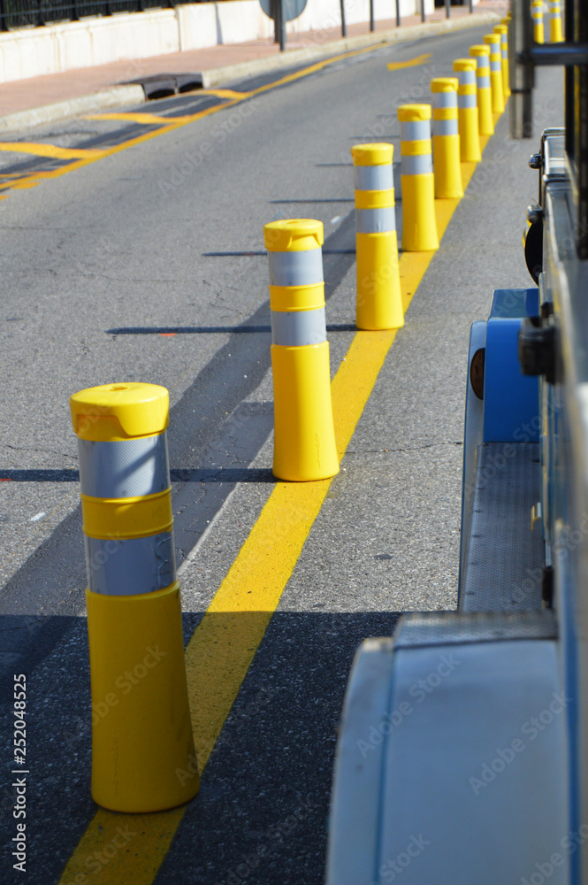 Yellow striped poles along the road divide the direction of traffic ...