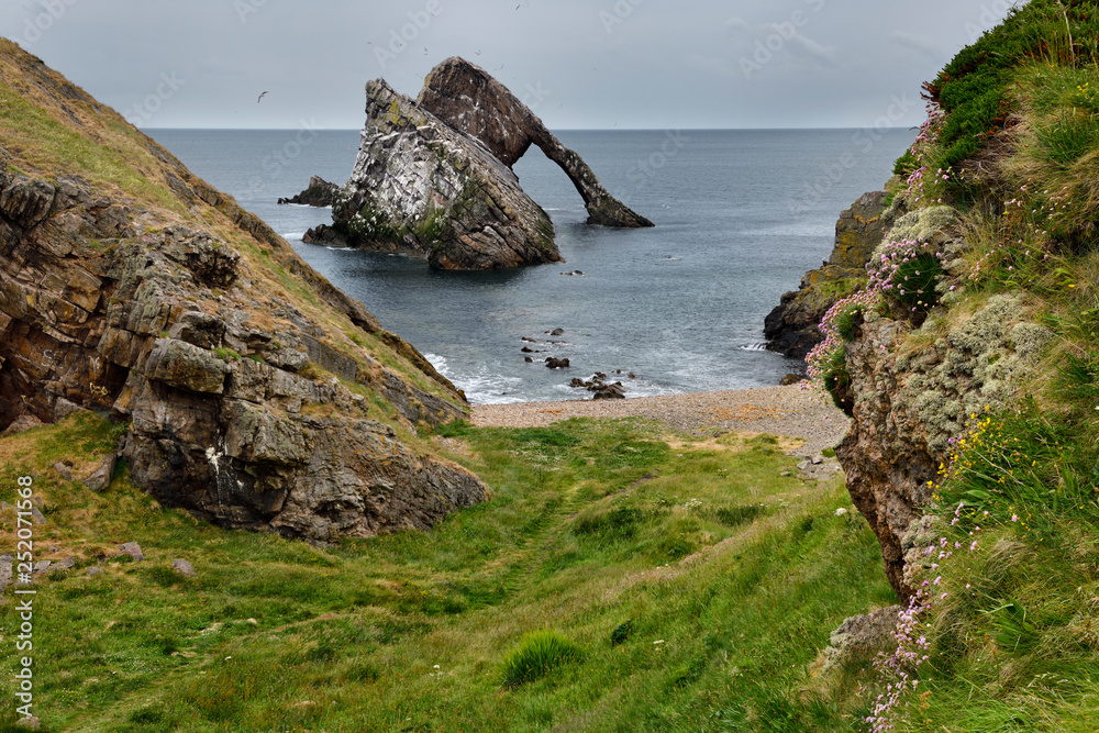 Bow Fiddle Rock quartzite sea arch with pebble beach and cliff with ...