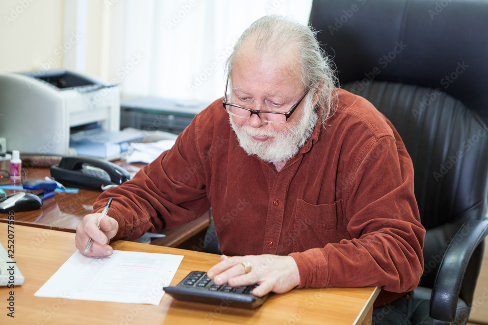 Mathematician senior man calculating and writing at the table at ...