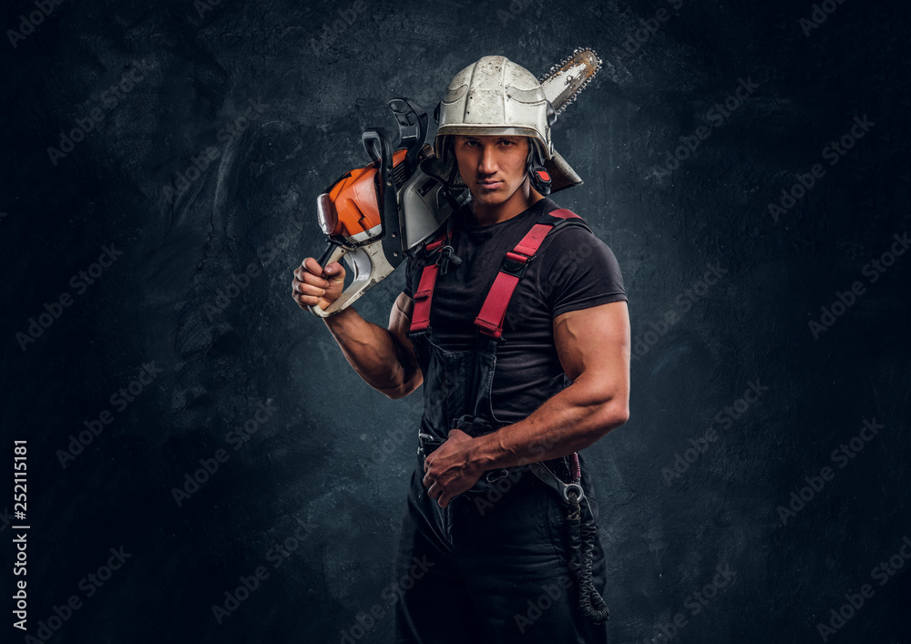 Brutal logger wearing protective clothes and helmet posing with a ...