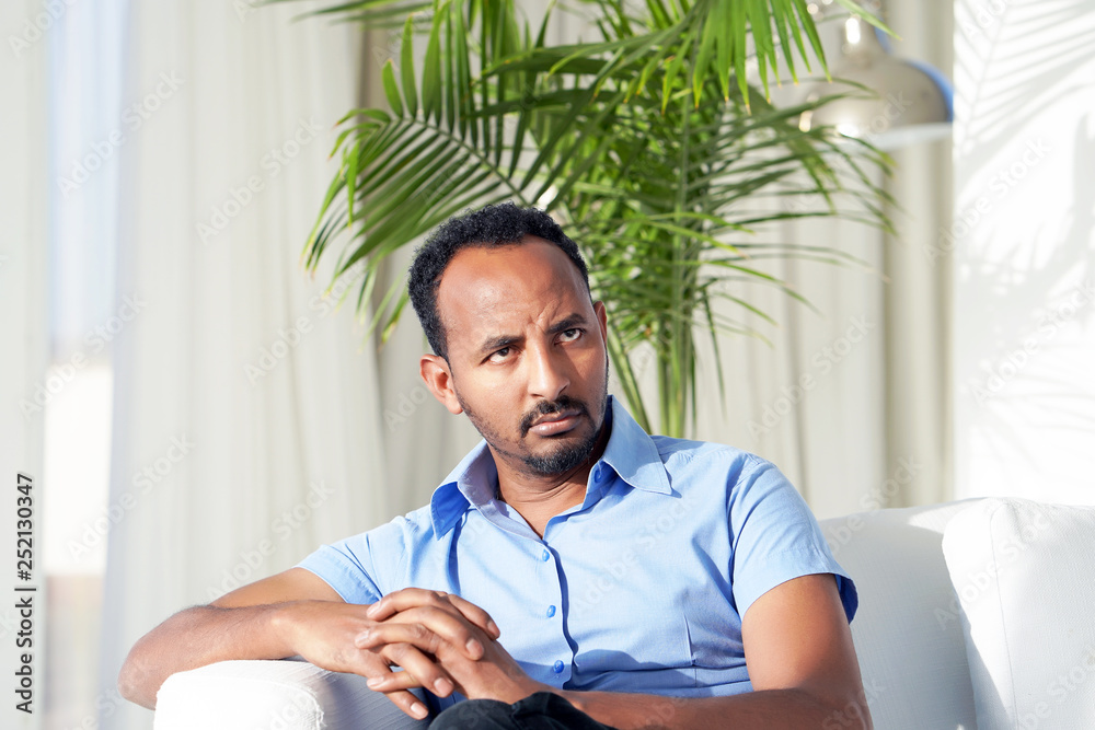 Lonely african man is sad sitting on the bed at home. Portrait of a sad ...