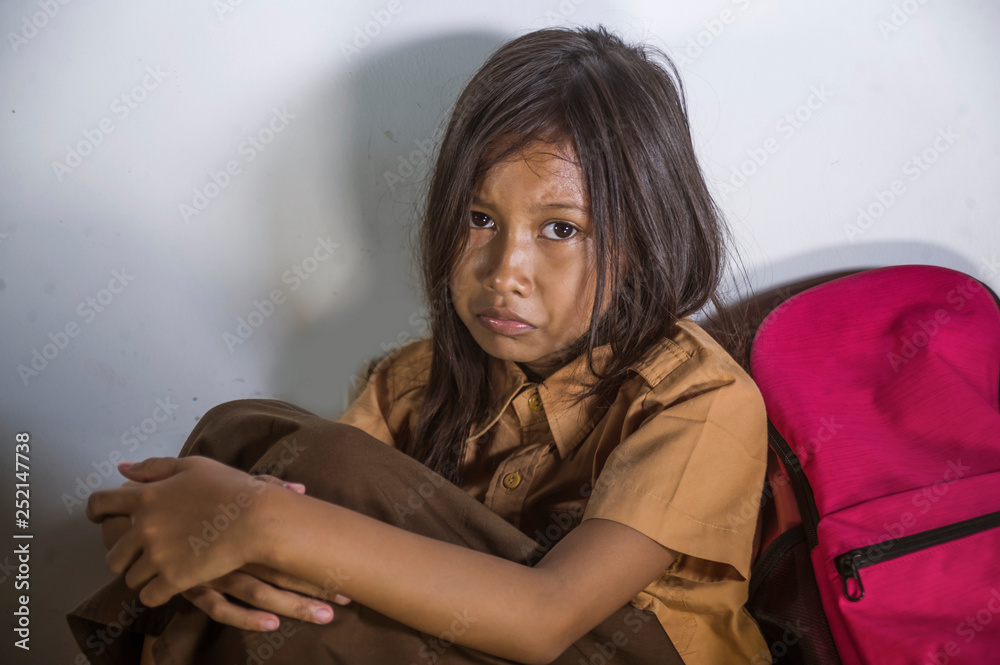 sad and depressed 8 or 9 years old child in school uniform sitting on ...