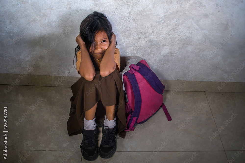 sad and depressed 8 or 9 years old child in school uniform sitting on ...