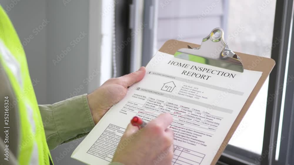Building inspector filling his report on a notepad at work wearing a ...