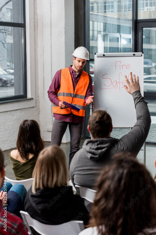Handsome fireman in helmet giving talk on briefing near white board ...