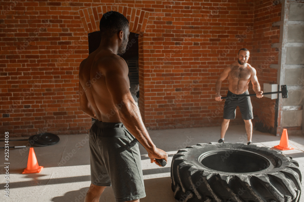 Caucasian athlete exercising with sledge hammer Hits on Tire with his ...