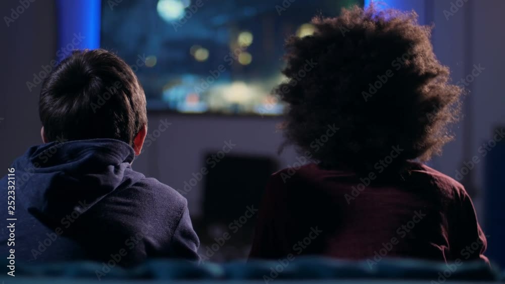 Back view teenager friends staring at wide screen playing video game ...