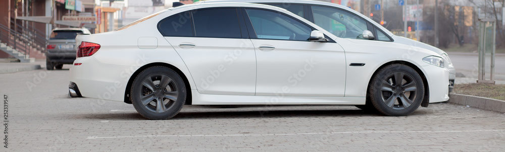 Side view of white car parked in paved parking lot area on blurred ...