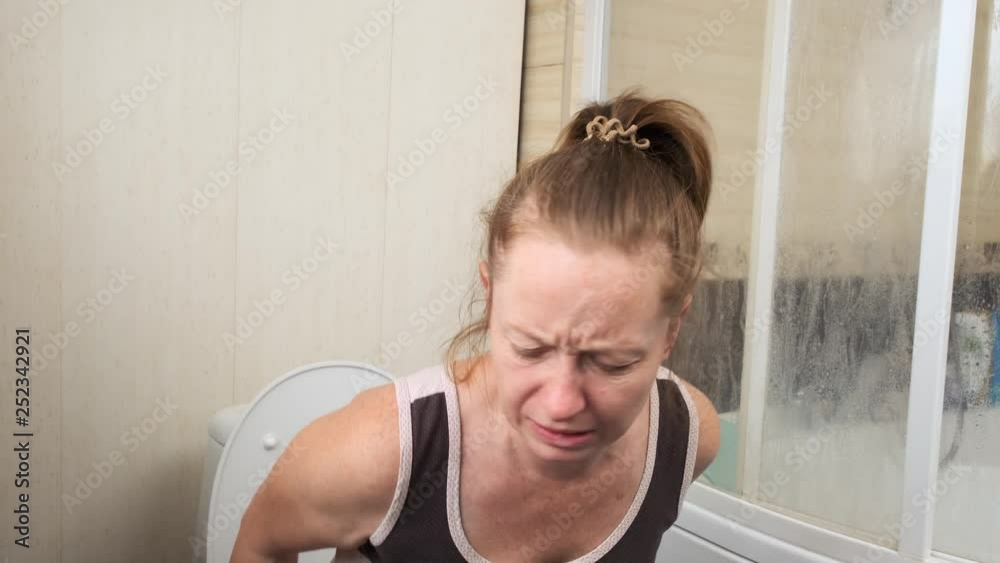 Girl sitting on the toilet contorts face from unpleasant odor of feces ...