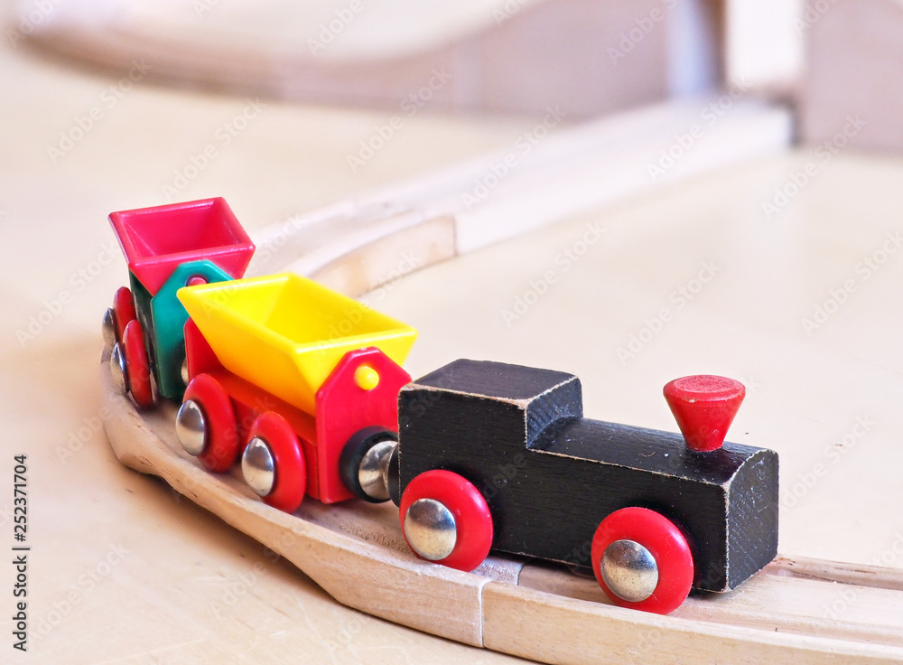 Wooden toy train running on miniature tracks. The black engine pulling ...