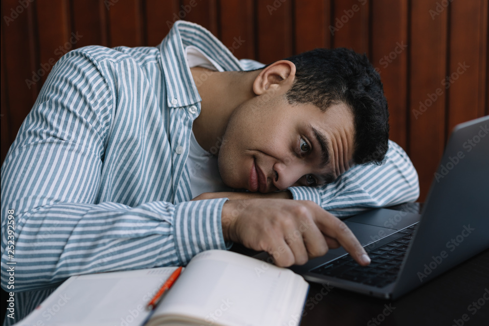 Unmotivated bored African American man freelancer using laptop computer ...