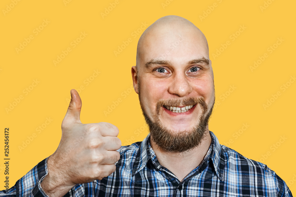 Happy bald smiling guy with a beard showing thumbs up on an isolated ...